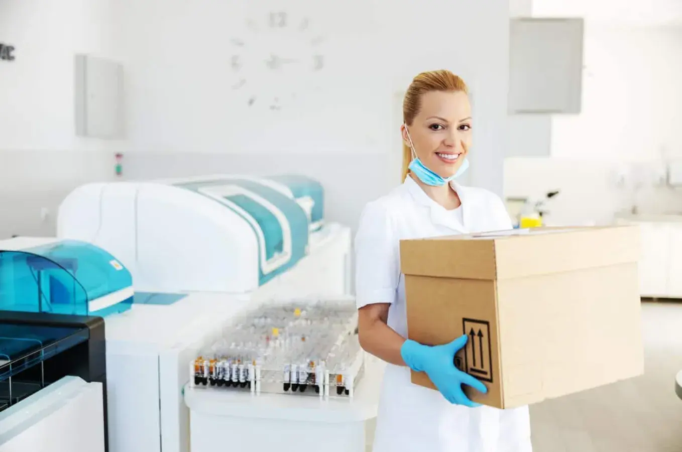 woman in lab holding box and smiling